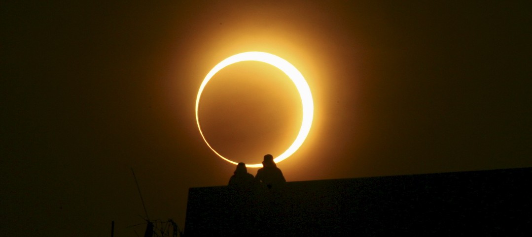 Two men sit on a bridge to watch an annular solar eclipse in Zhengzhou ...